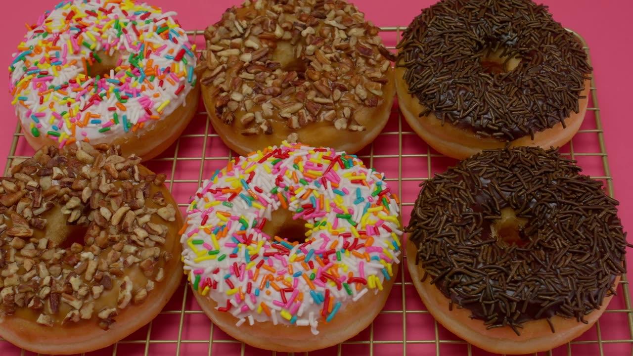 Donuts with various types of icing in a close up - One News Page VIDEO